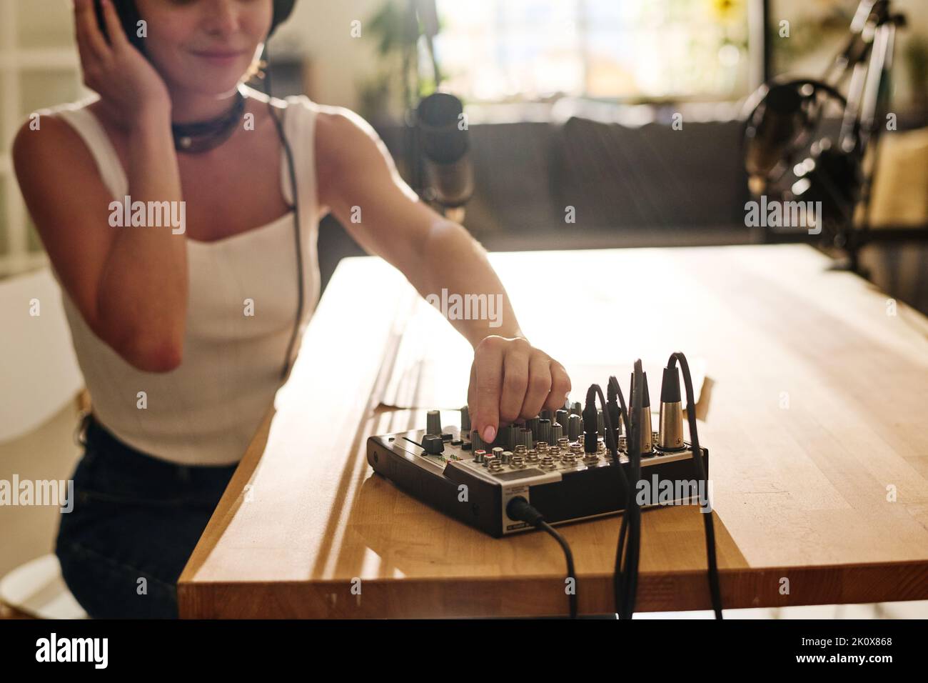 Hand of young woman rotating mixer console on soundboard by workplace ...