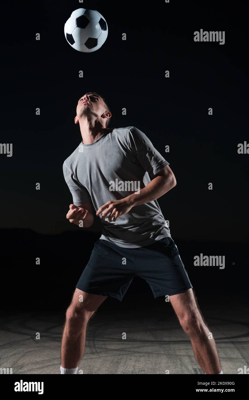 portrait of a young handsome soccer player man on a street playing with ...