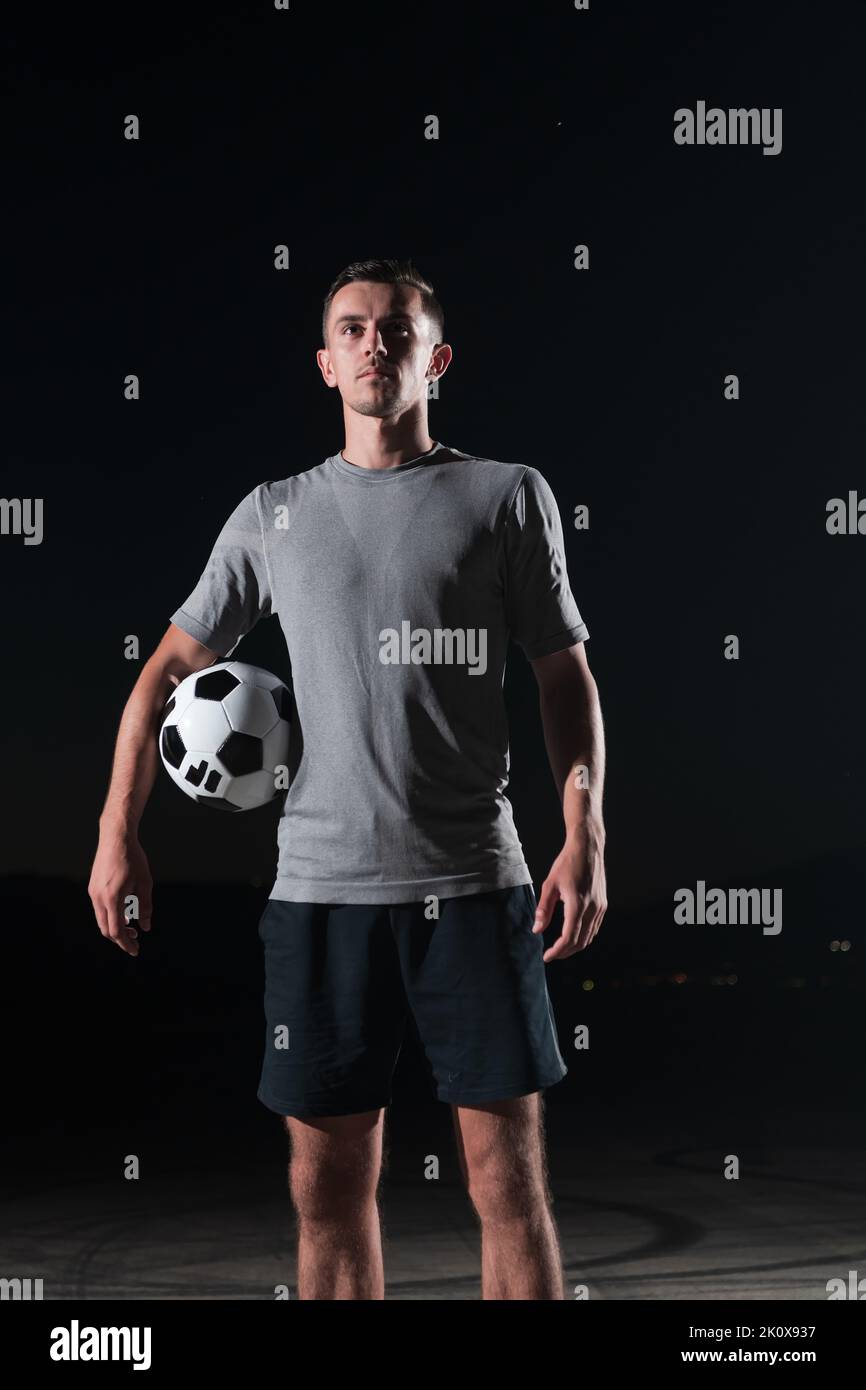 portrait of a young handsome soccer player man on a street playing with ...
