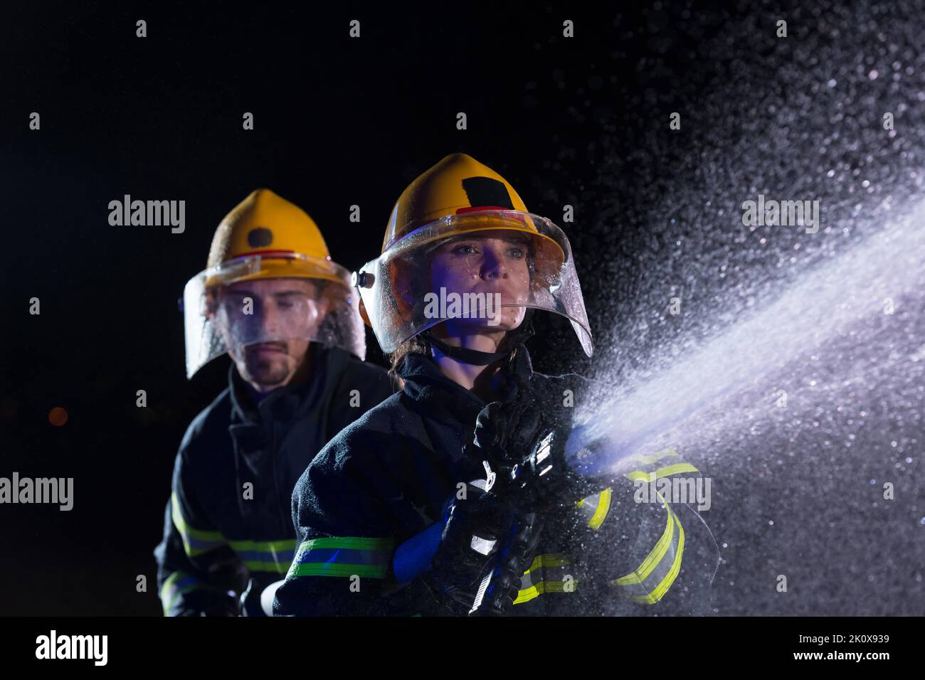 Firefighters using a water hose to eliminate a fire hazard. Team of ...