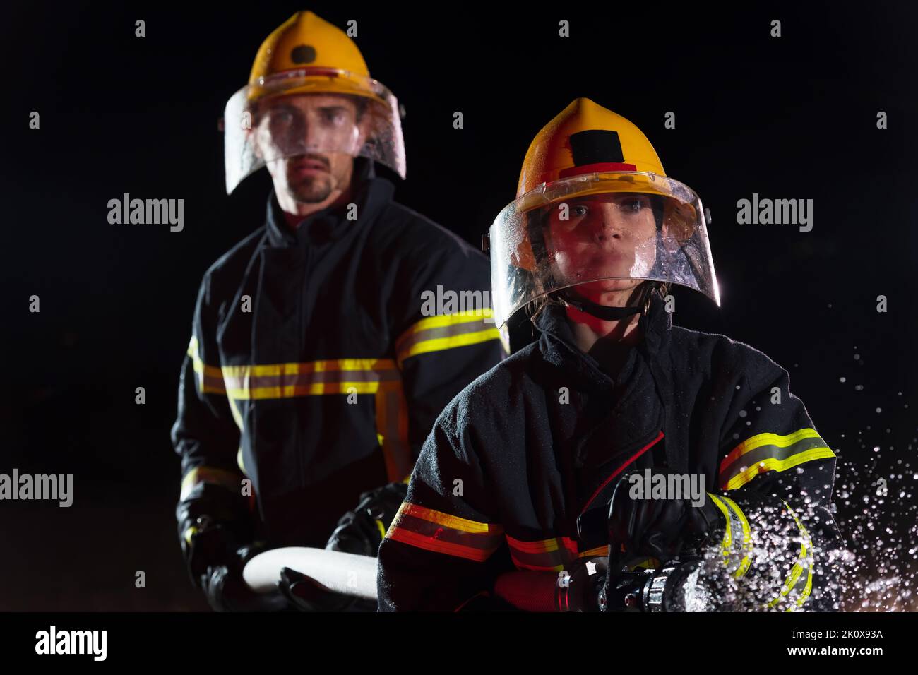 Firefighters using a water hose to eliminate a fire hazard. Team of ...