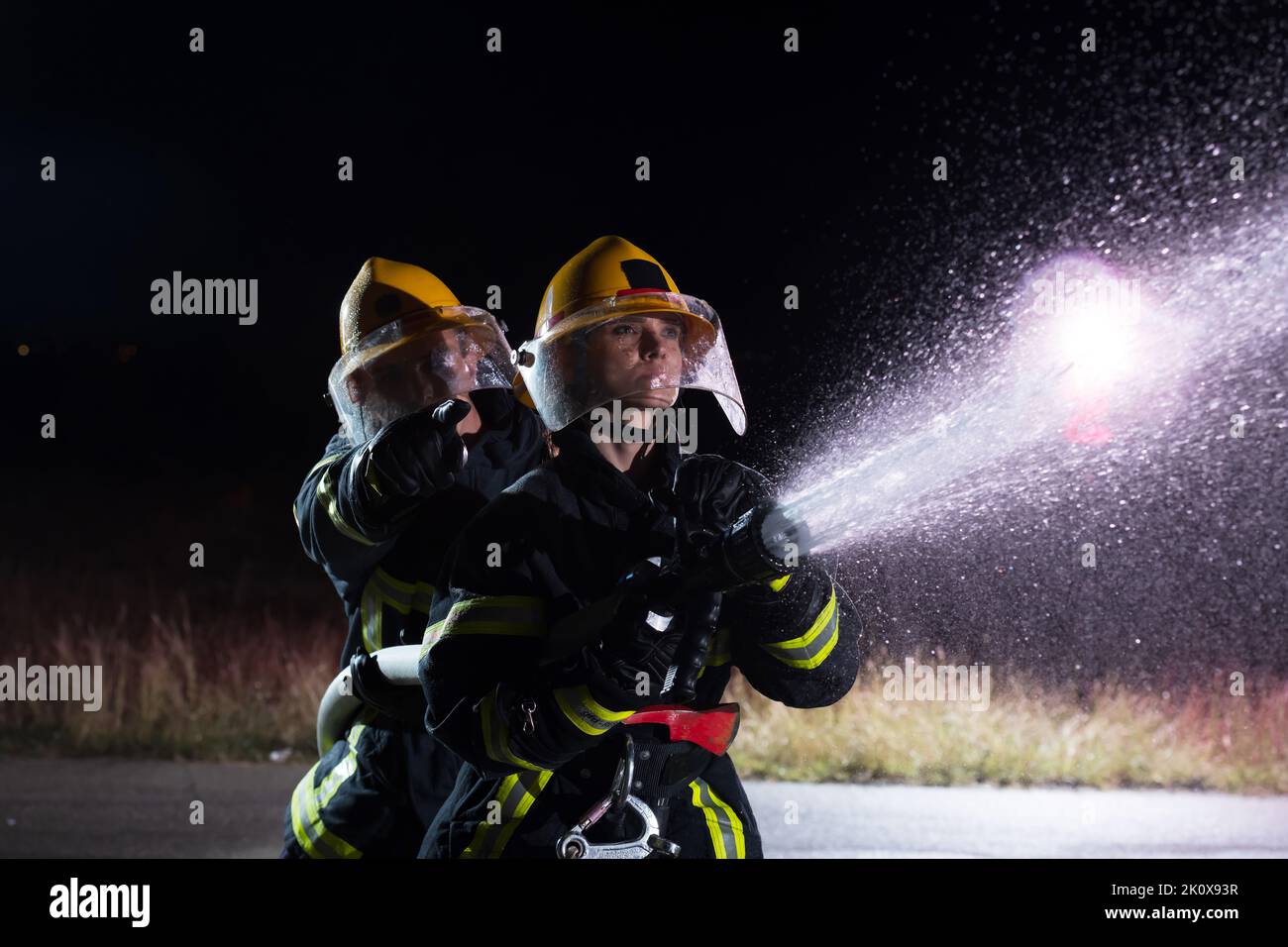 Firefighters using a water hose to eliminate a fire hazard. Team of ...
