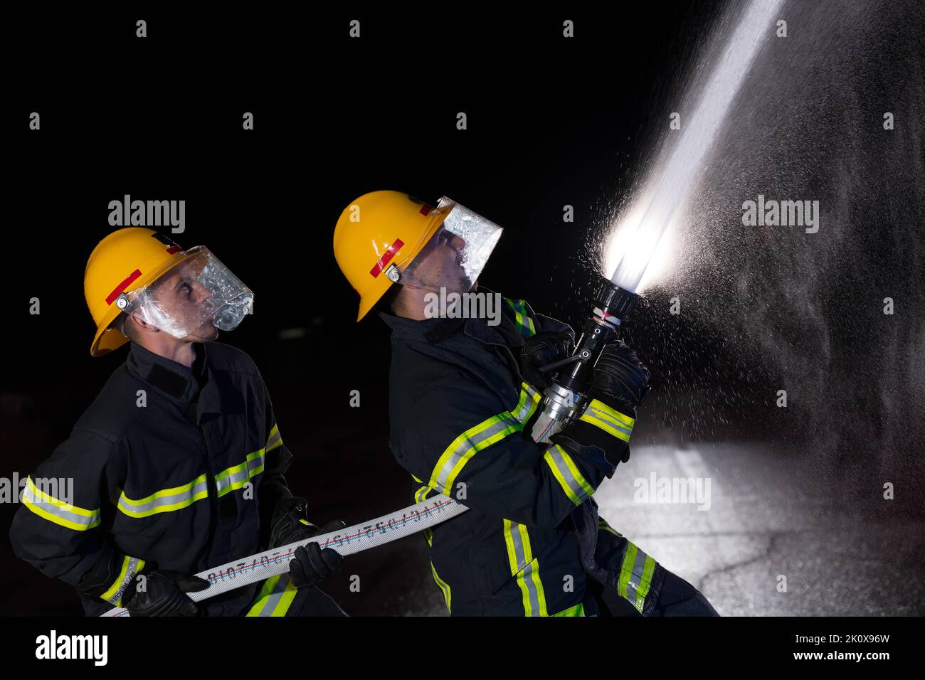 Firefighters use a water hose to eliminate a fire hazard. Team of ...