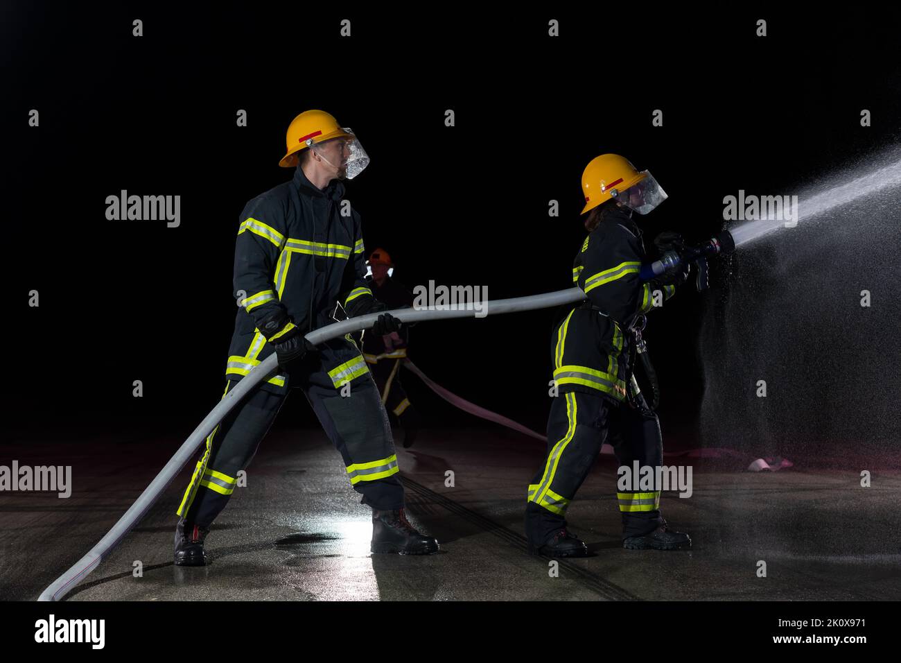 Firefighters using a water hose to eliminate a fire hazard. Team of ...