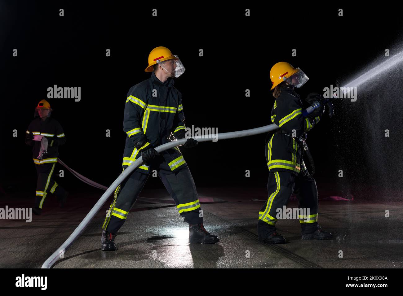 Firefighters using a water hose to eliminate a fire hazard. Team of ...