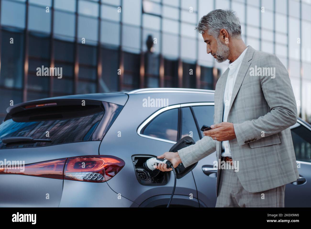 Man holding power supply cable at electric vehicle charging station ...