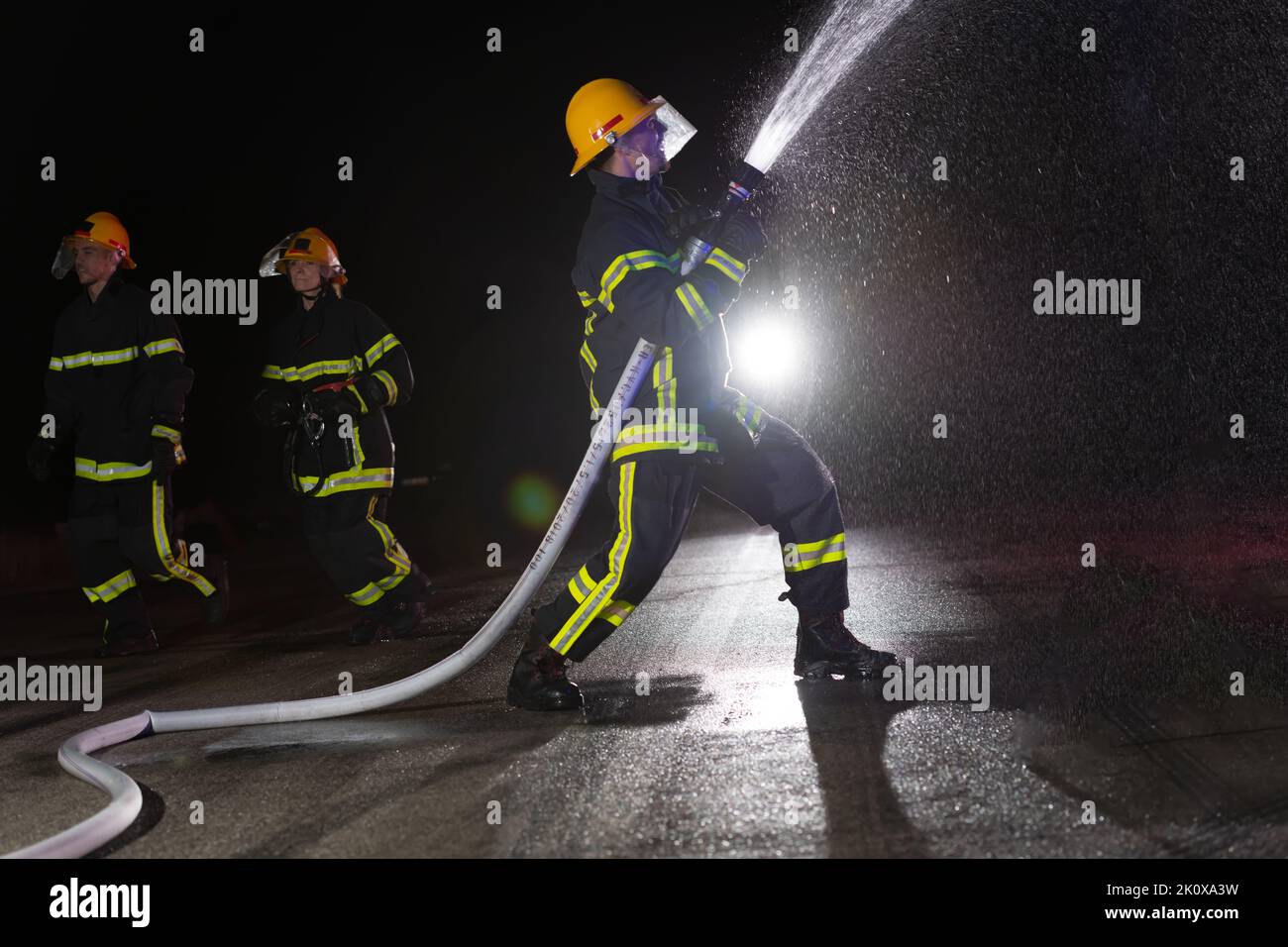 Firefighters use a water hose to eliminate a fire hazard. Team of ...