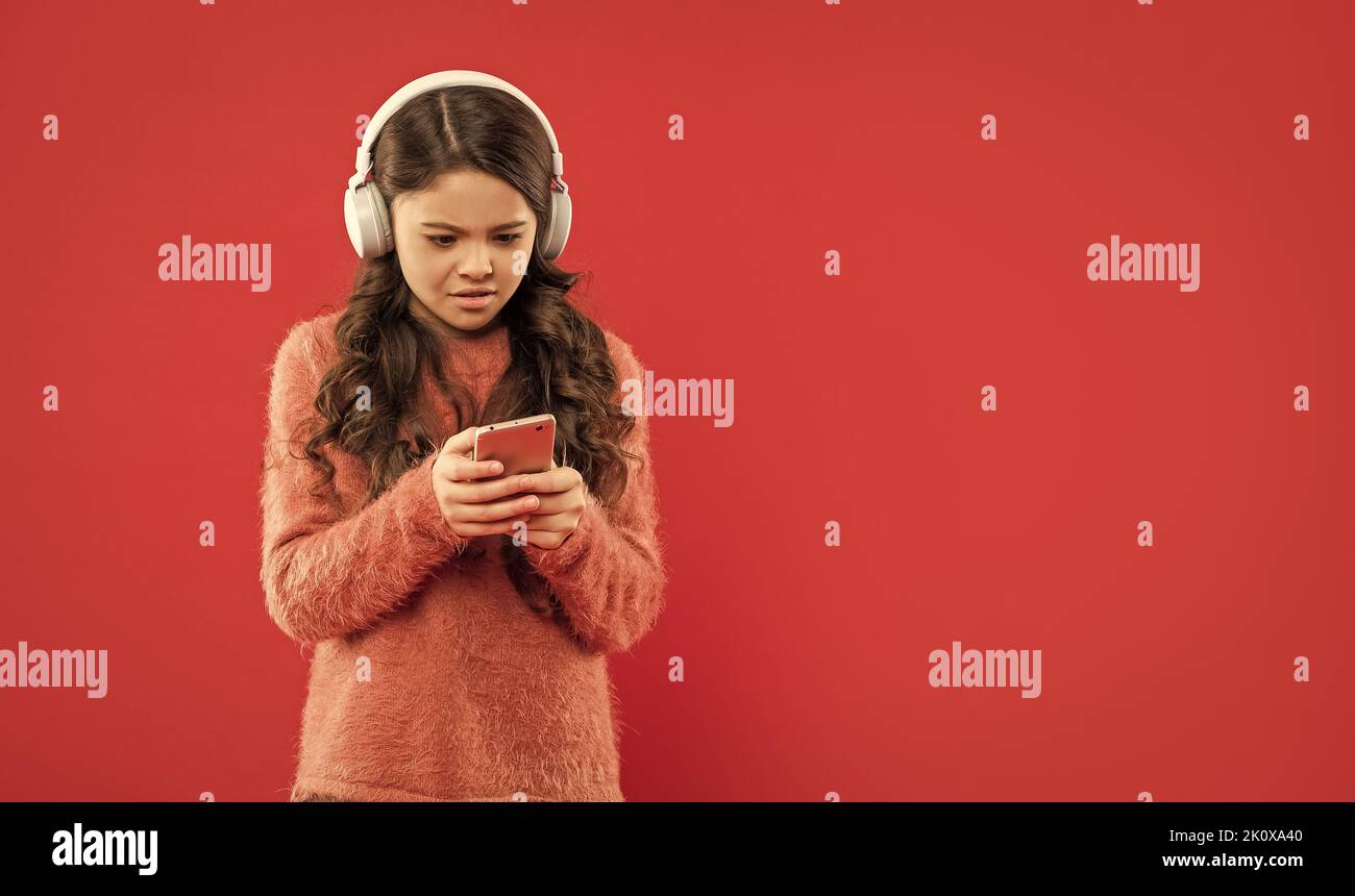 busy teen girl in sweater in headphones for listening music texting in ...