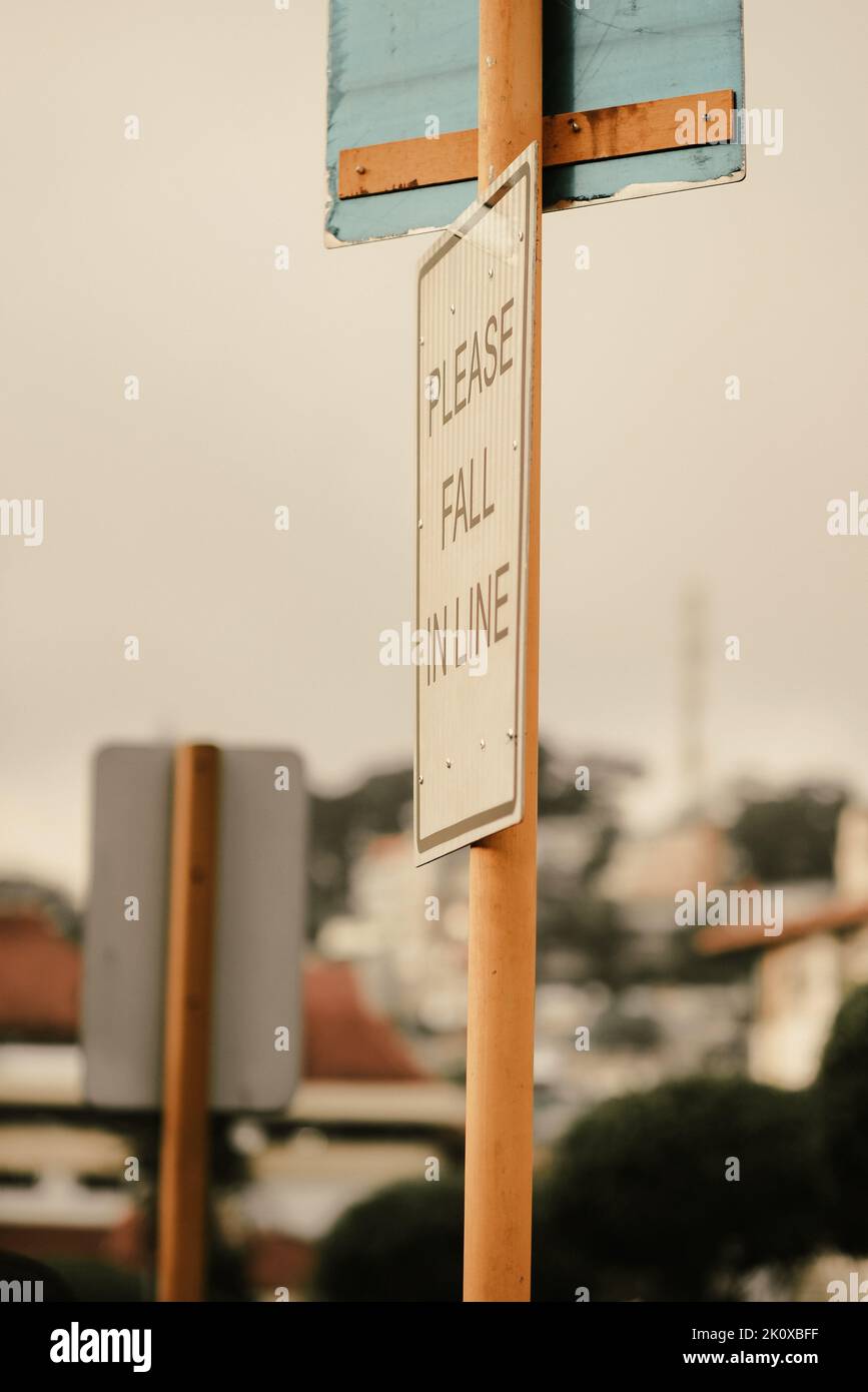 A vertical closeup of a road sign with "please fall in line ...