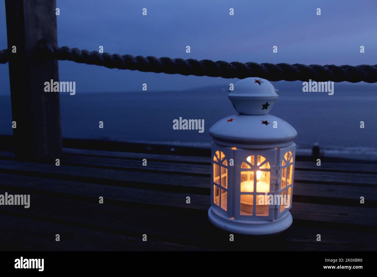 Lantern with candle light inside on wooden bridge in the beach at blue ...
