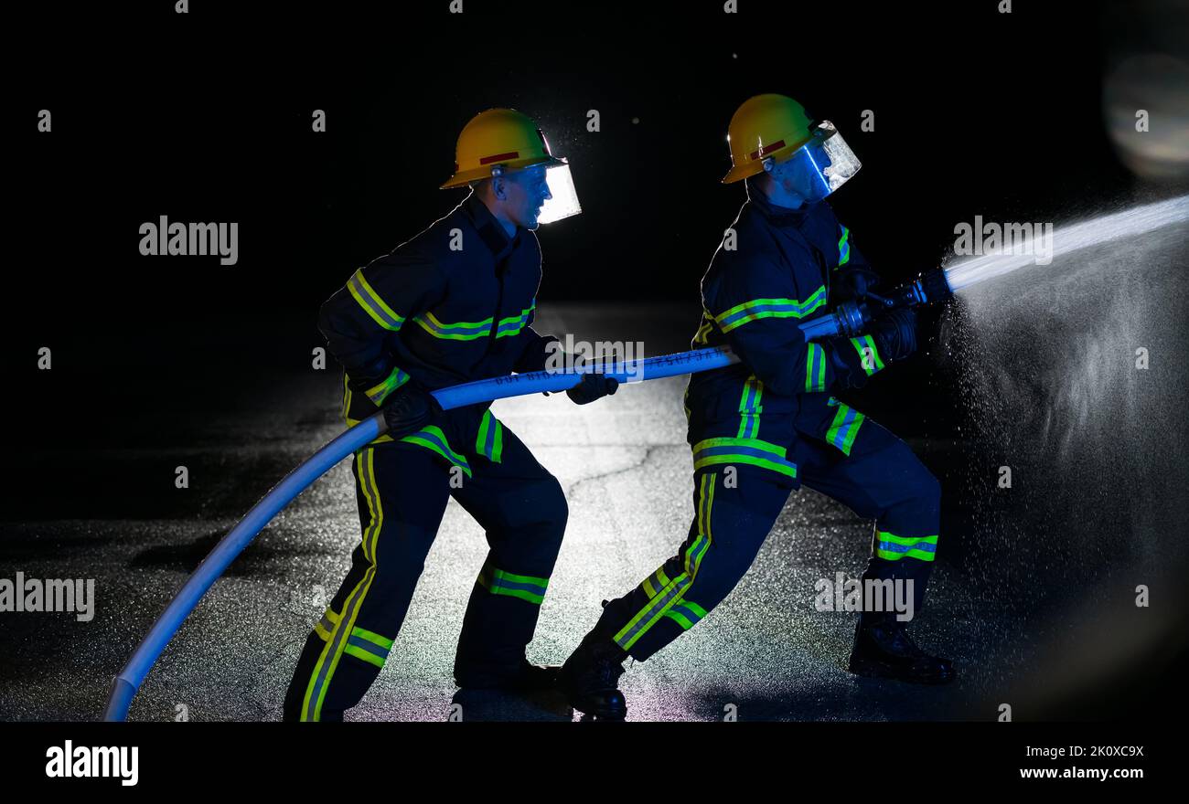Firefighters use a water hose to eliminate a fire hazard. Team of ...