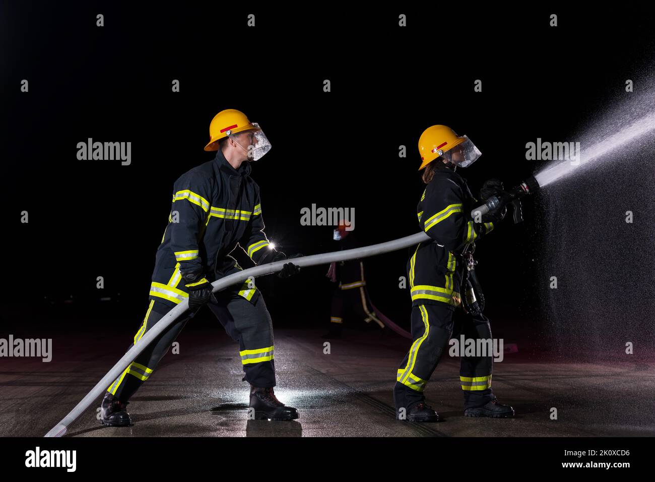 Firefighters using a water hose to eliminate a fire hazard. Team of ...