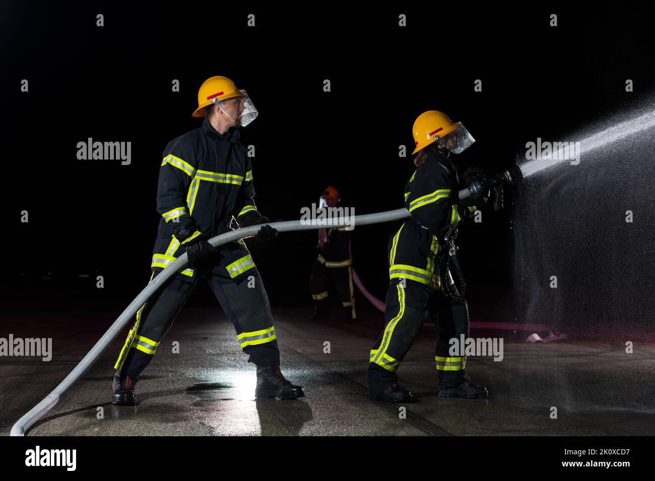 Firefighters using a water hose to eliminate a fire hazard. Team of ...
