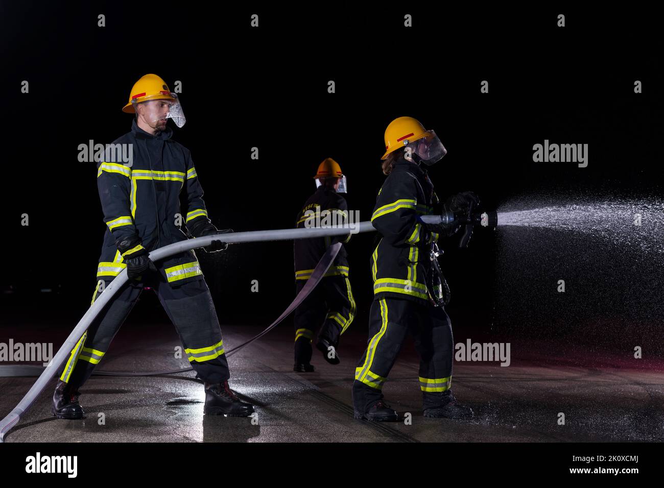 Firefighters using a water hose to eliminate a fire hazard. Team of ...