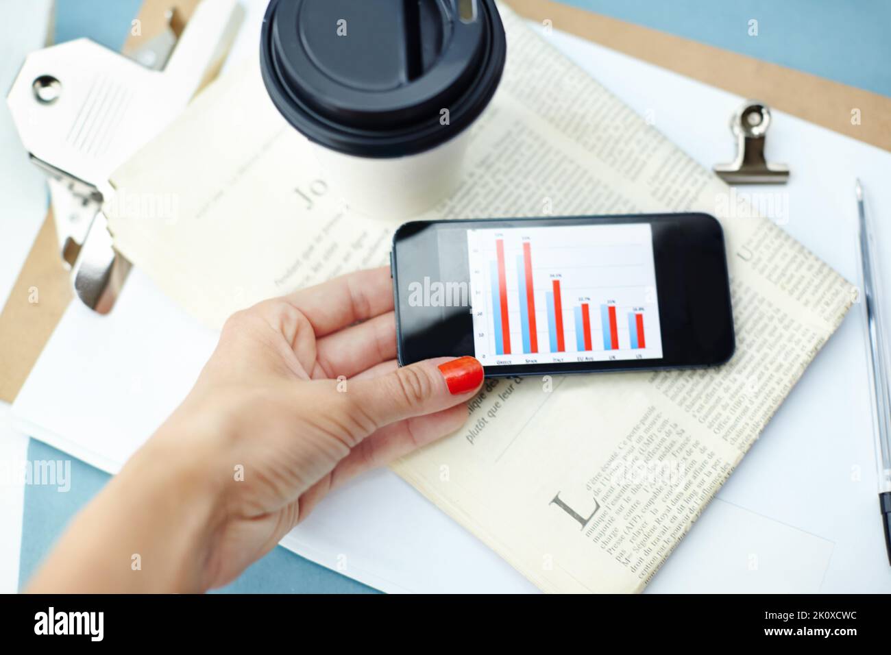 Business on the go. Hand holding smartphone with bar chart on screen ...