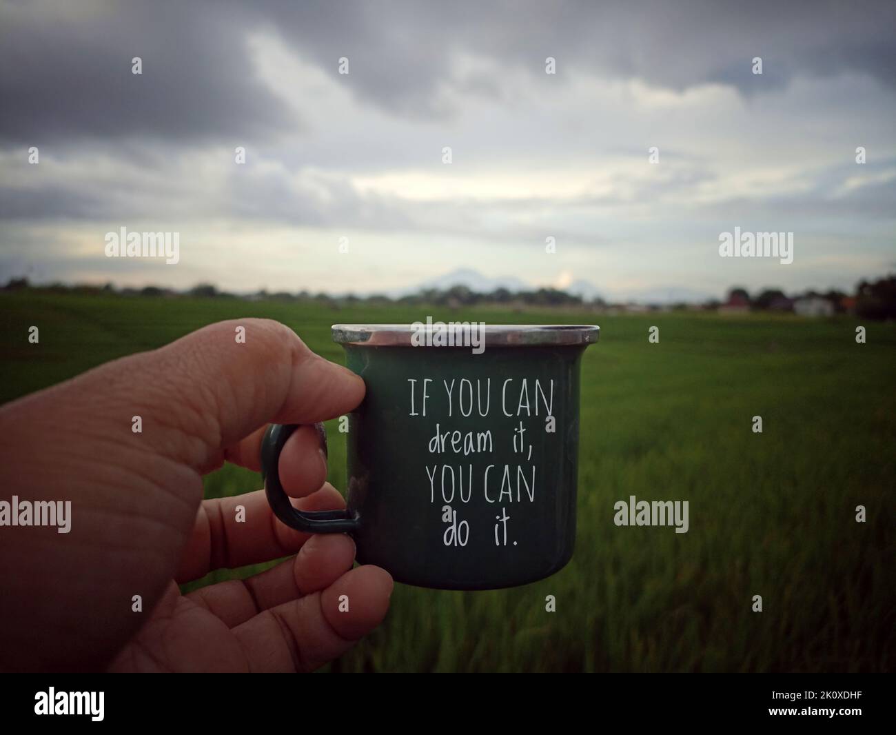 Motivation words on coffee cup. Person holding small green cup in hand ...