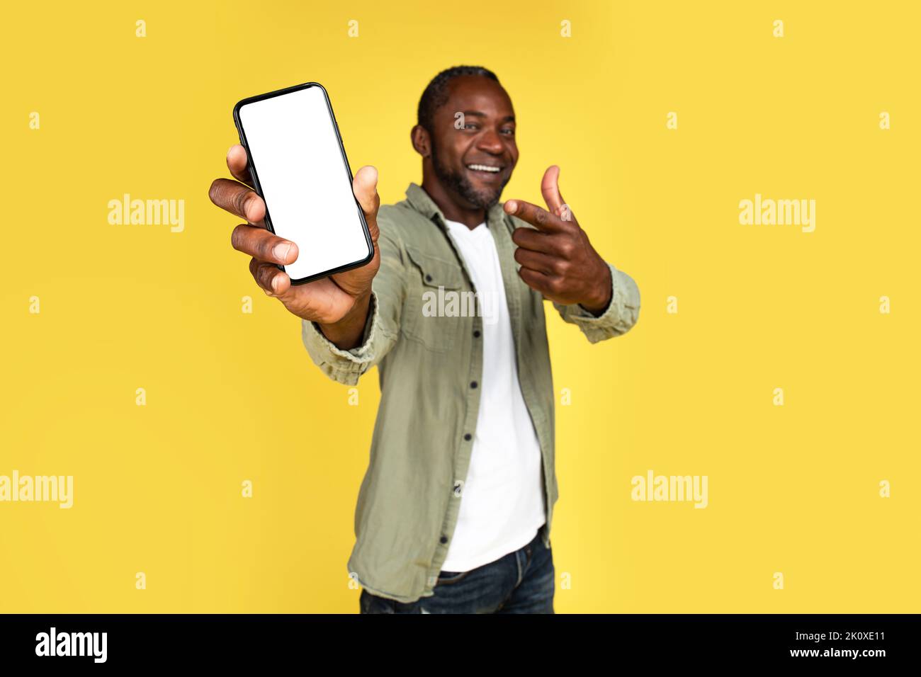 Smiling adult black guy in casual rejoices to online victory, show ...