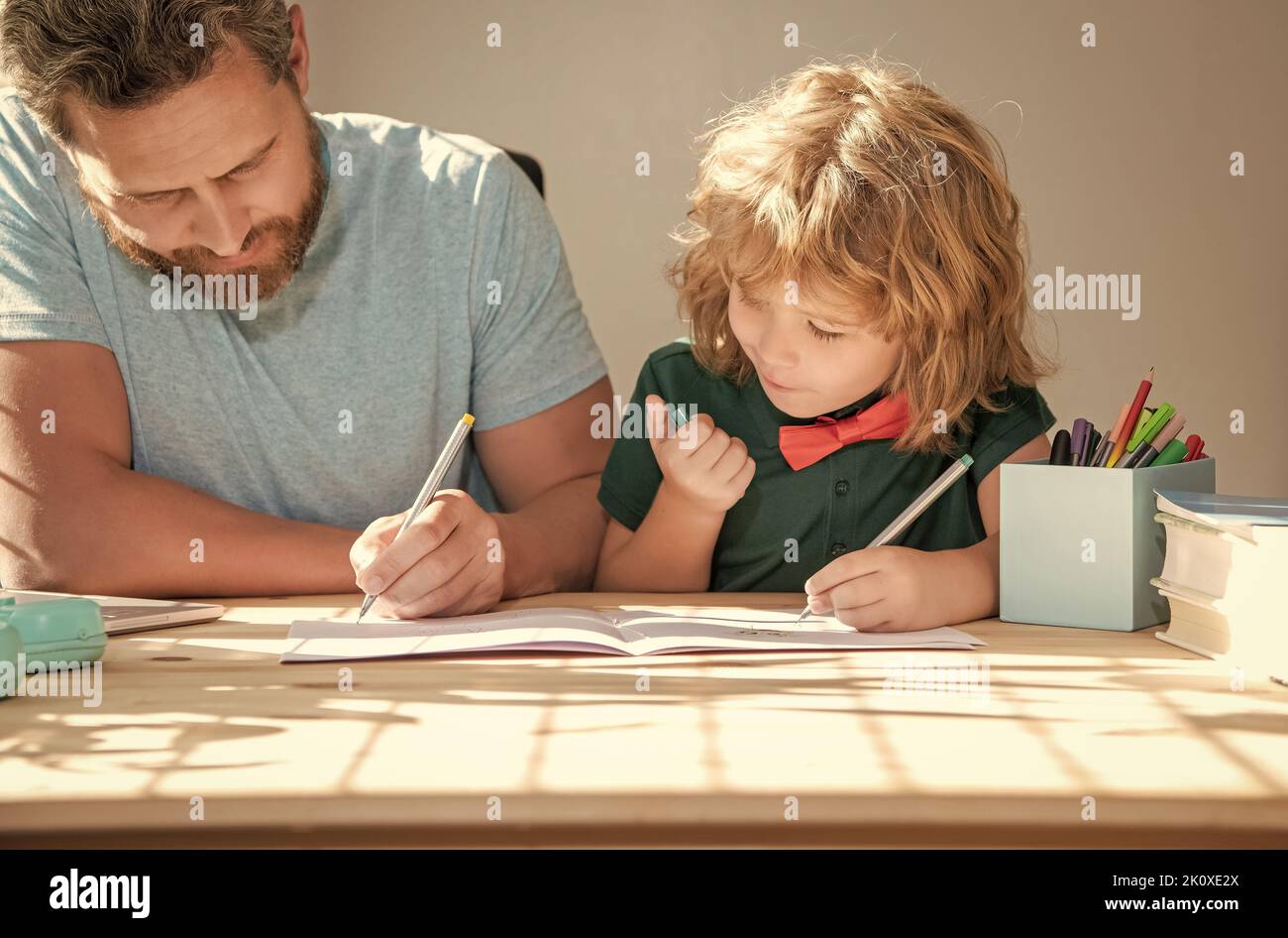 bearded father writing school homework with his child son in classroom ...