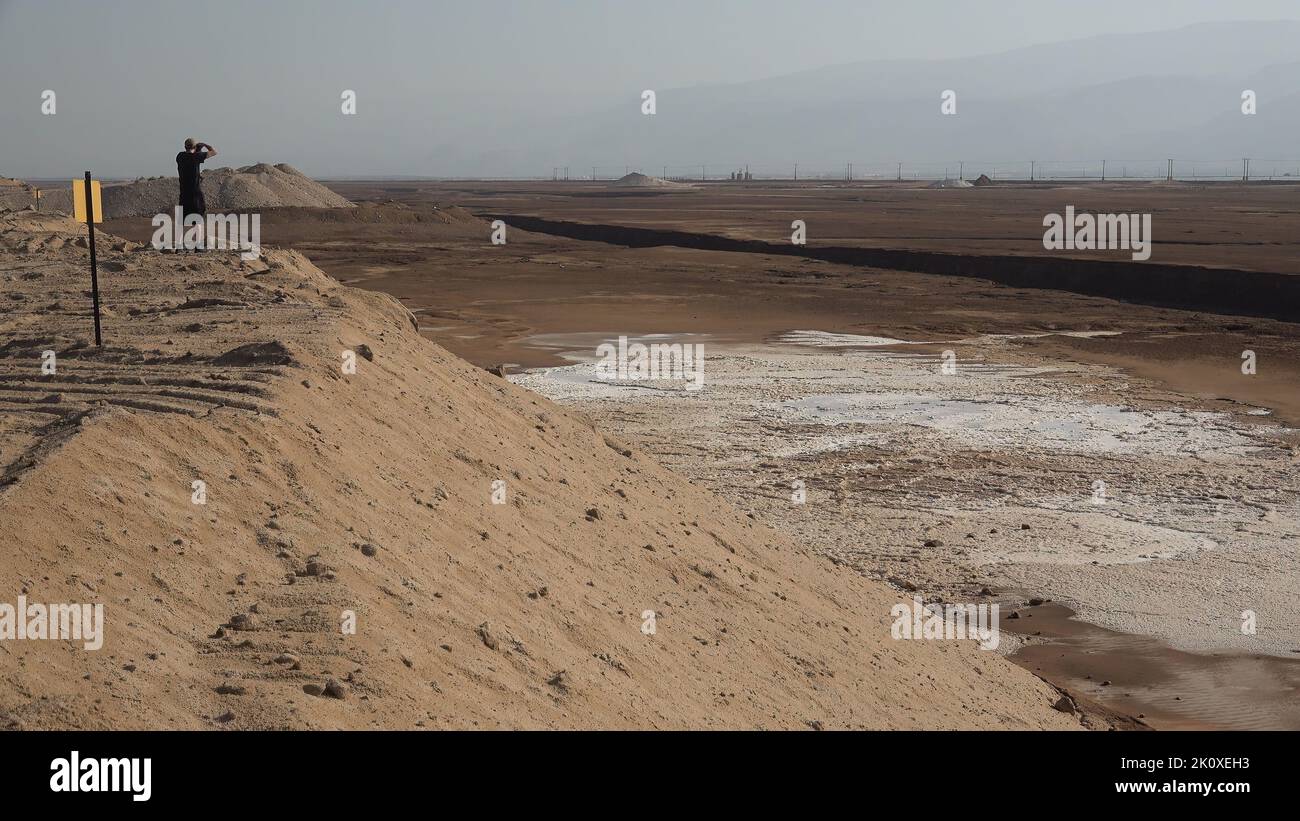 An Israeli man takes photos from the salt wall barrier along the border ...