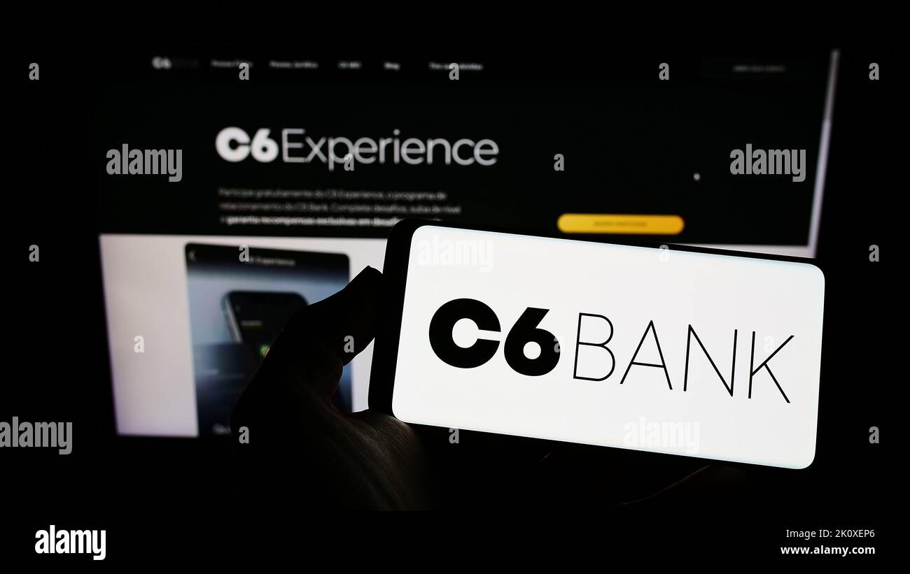 Person holding smartphone with logo of Brazilian company BANCO C6 S.A ...