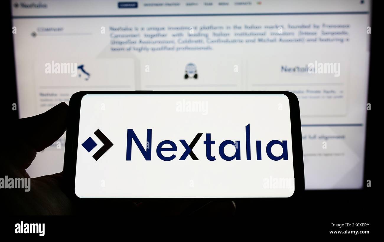 Person holding mobile phone with logo of Italian investment company ...