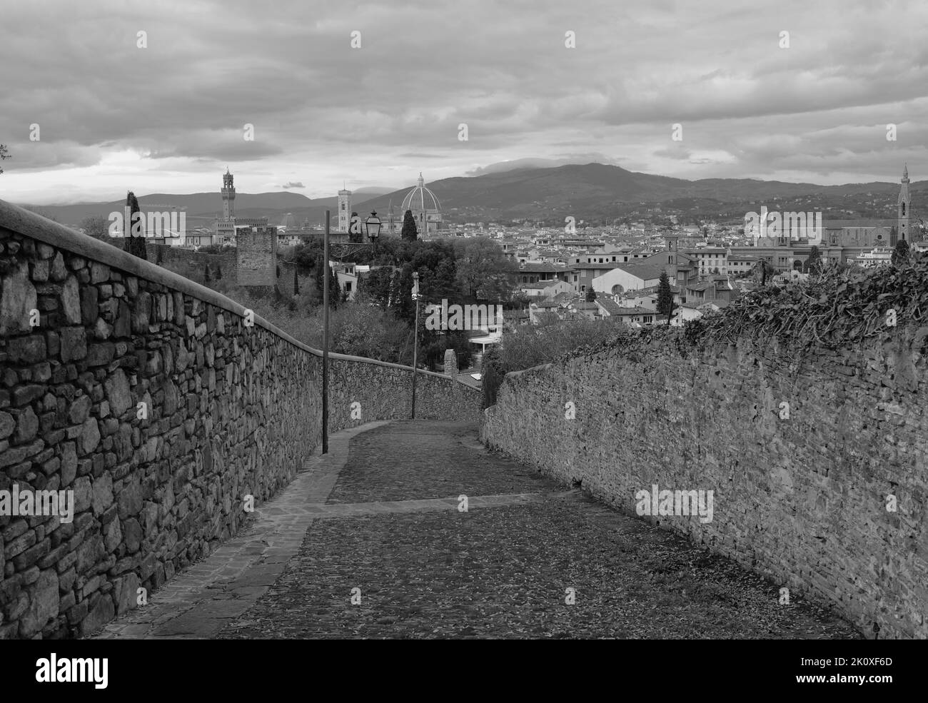 a greyscale of a rocky pathway with high rise walls through a town ...