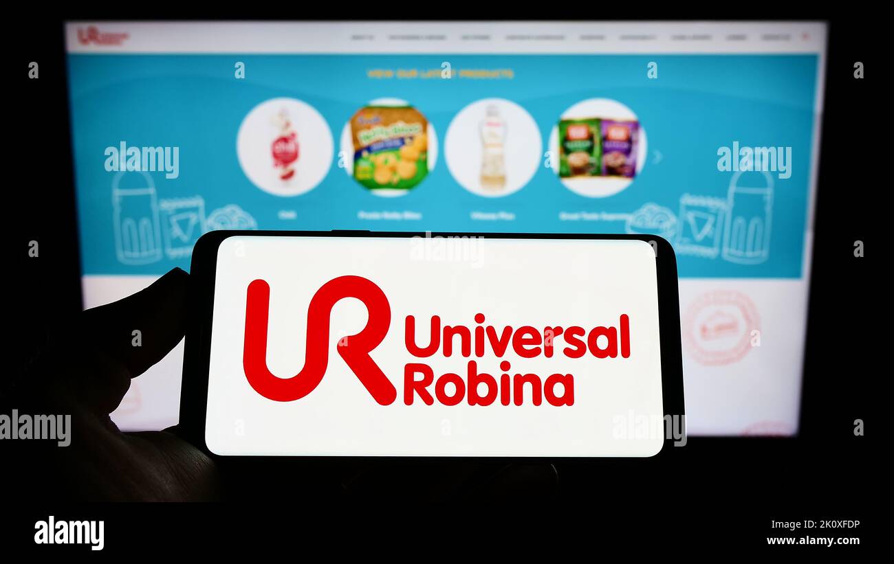 Person holding mobile phone with logo of company Universal Robina ...