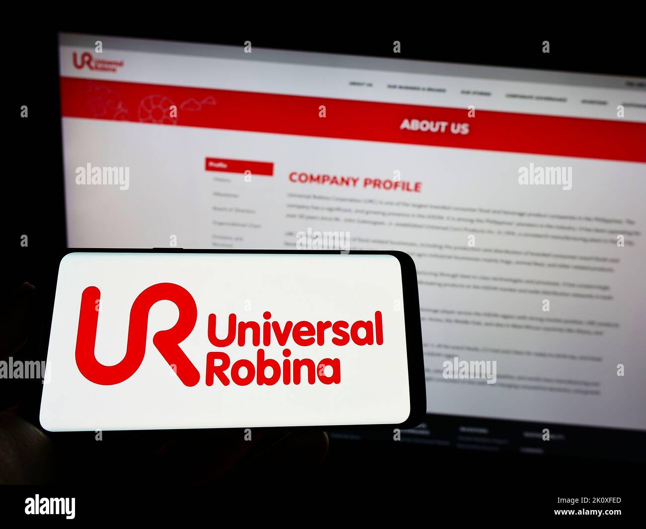 Person holding cellphone with logo of company Universal Robina ...