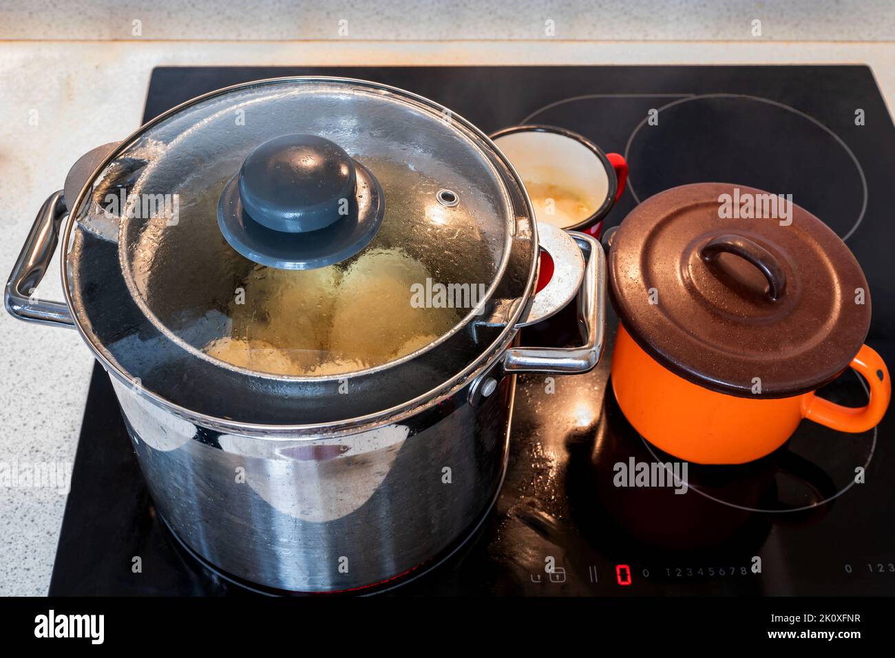 Boiled sweet plum dumplings in pot with lid on hot ceramic hob, melted ...