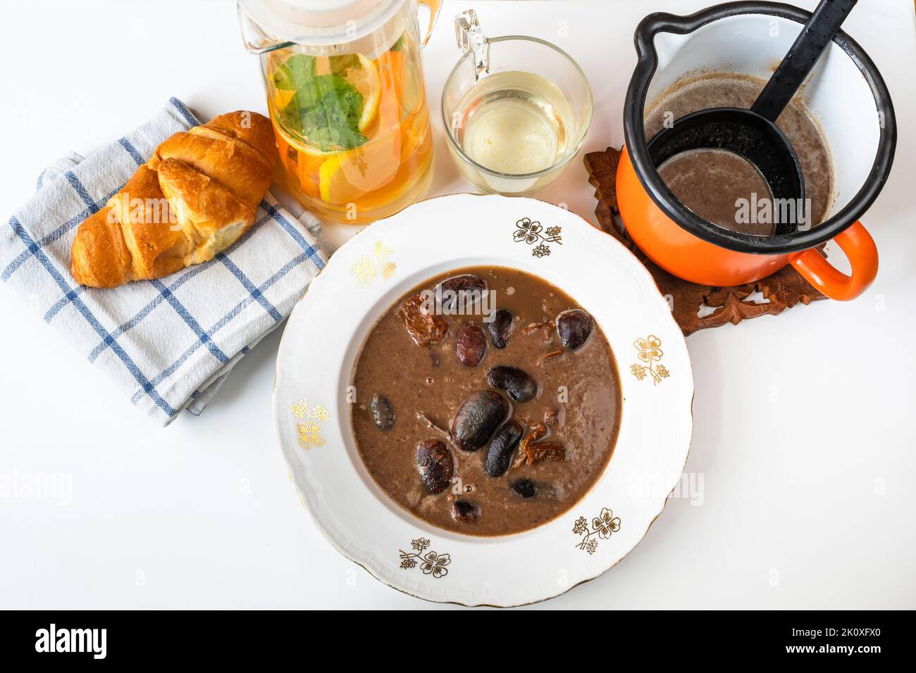 Giant bean soup with dried tomato in plate and in orange pot with ladle ...