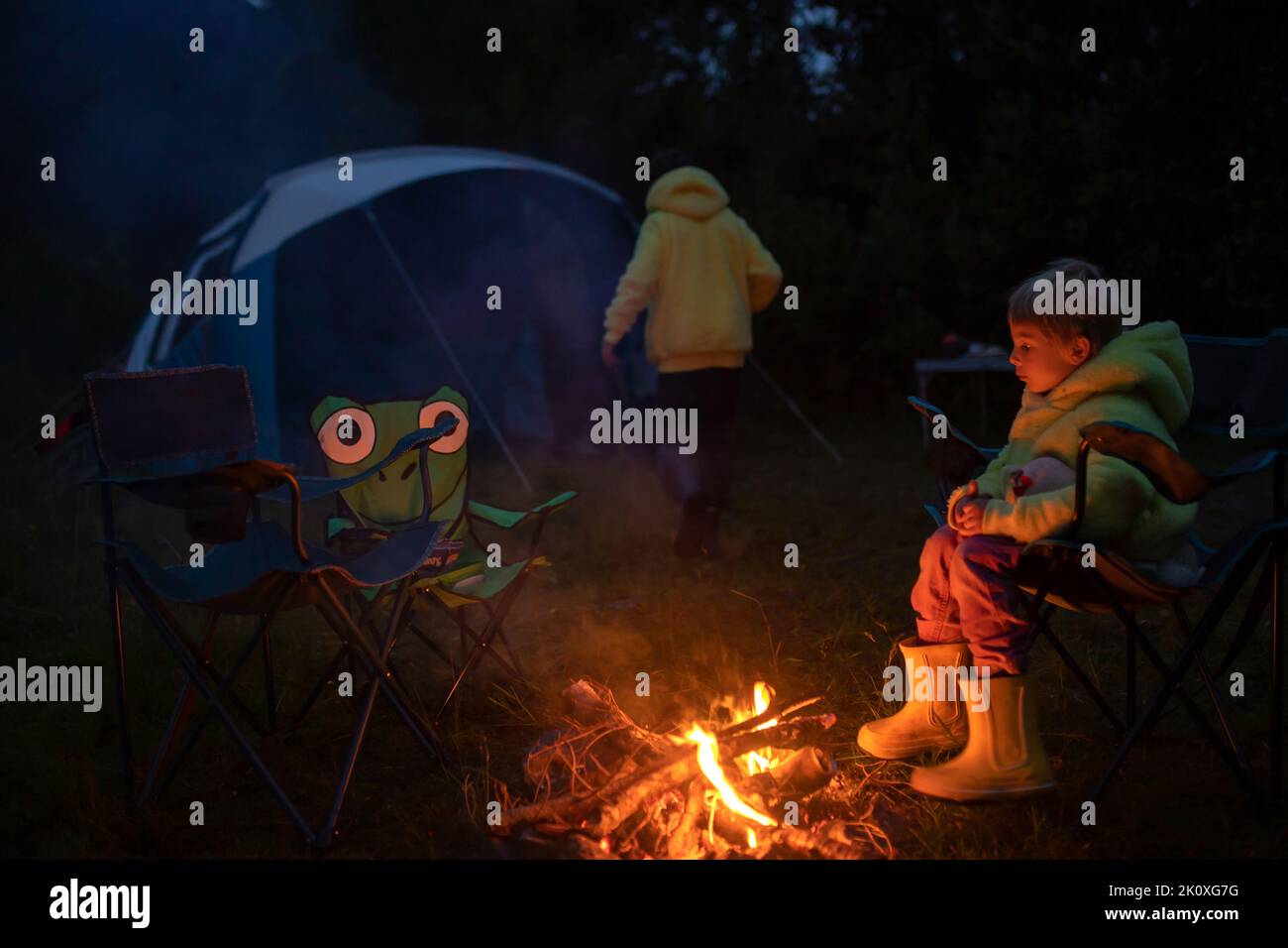 Kids, sitting around campfire at night, enjoying wild camping, family ...