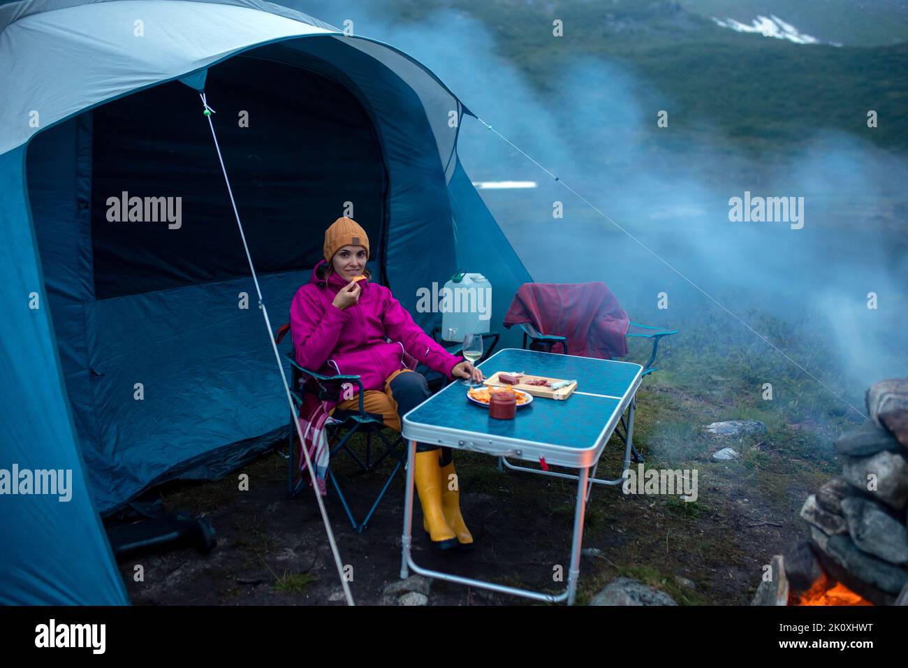 Woman, sitting around campfire at night, enjoying wild camping, family ...