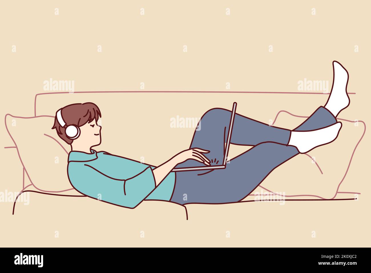 Happy man lying on couch wear headphones work on laptop. Smiling guy ...