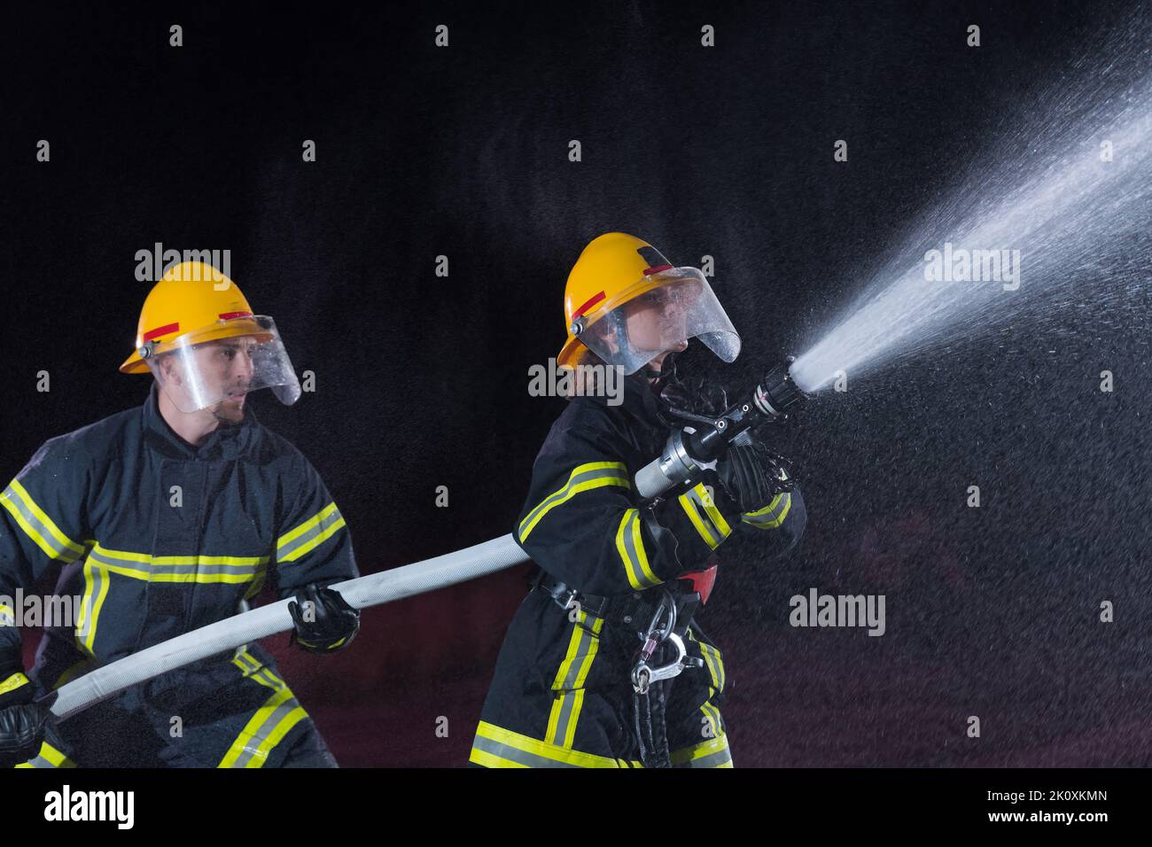 Firefighters using a water hose to eliminate a fire hazard. Team of ...