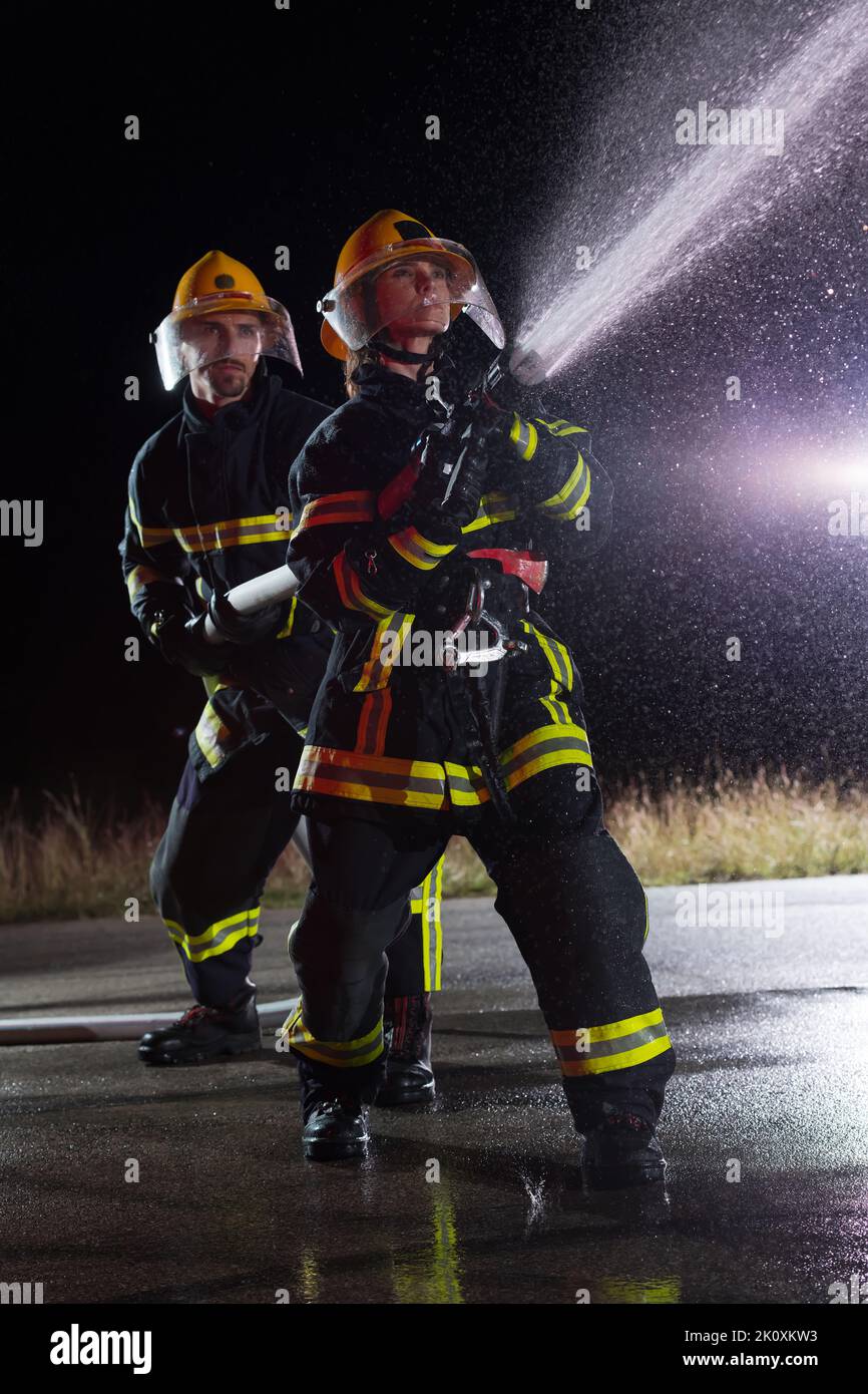 Firefighters using a water hose to eliminate a fire hazard. Team of ...