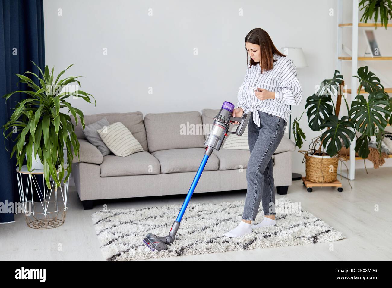 Happy cheerful young Caucasian beautiful woman vacuuming floor and ...