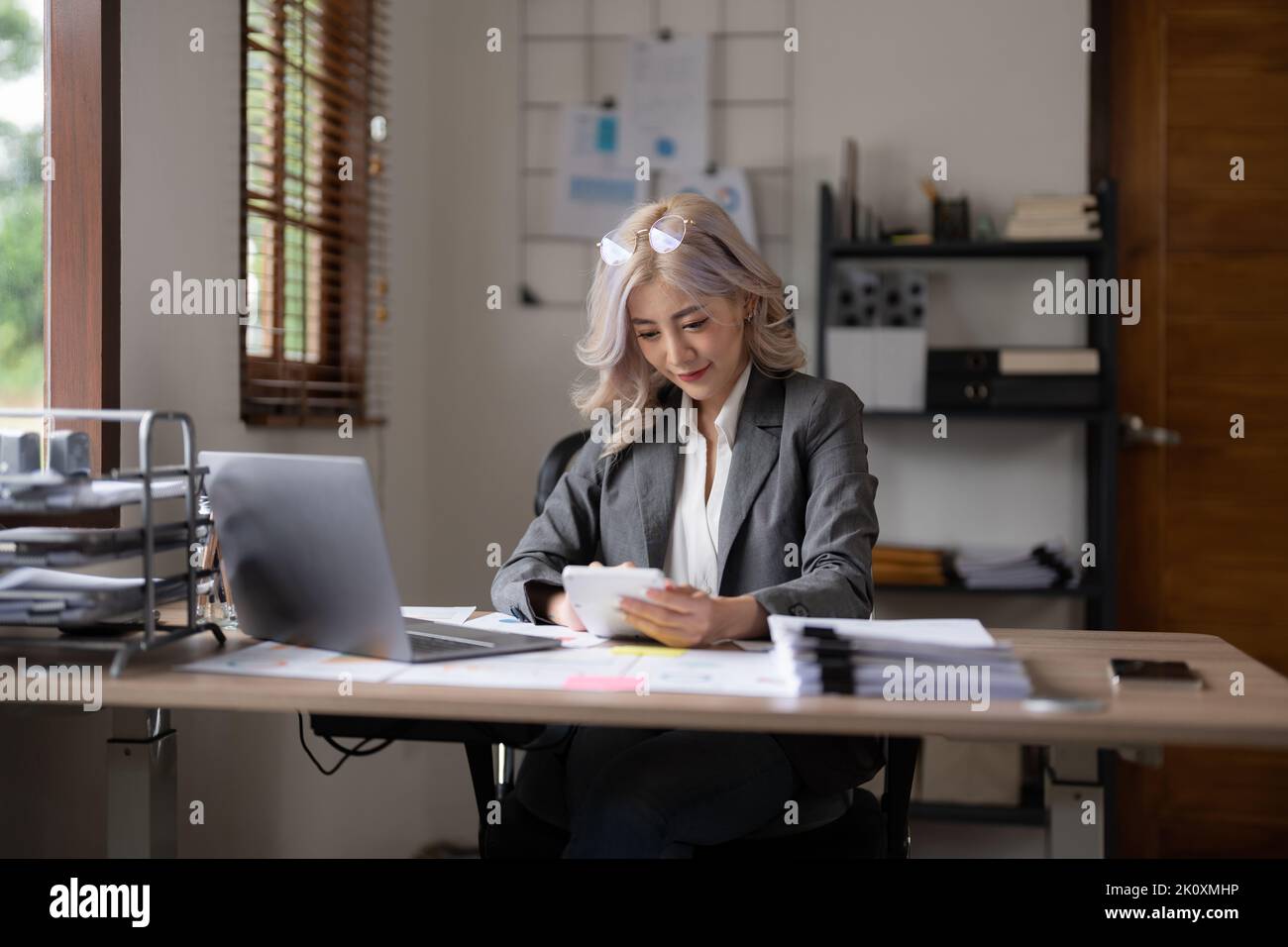 Beautiful asian businesswoman analyzes charts using laptop and ...