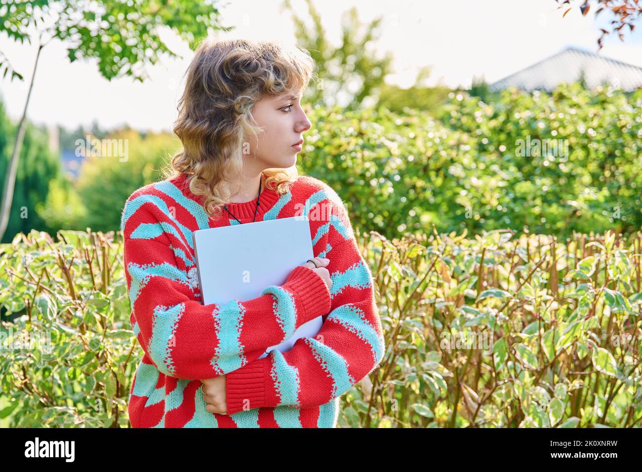 Teenage student girl with laptop in hands, looking in profile Stock ...