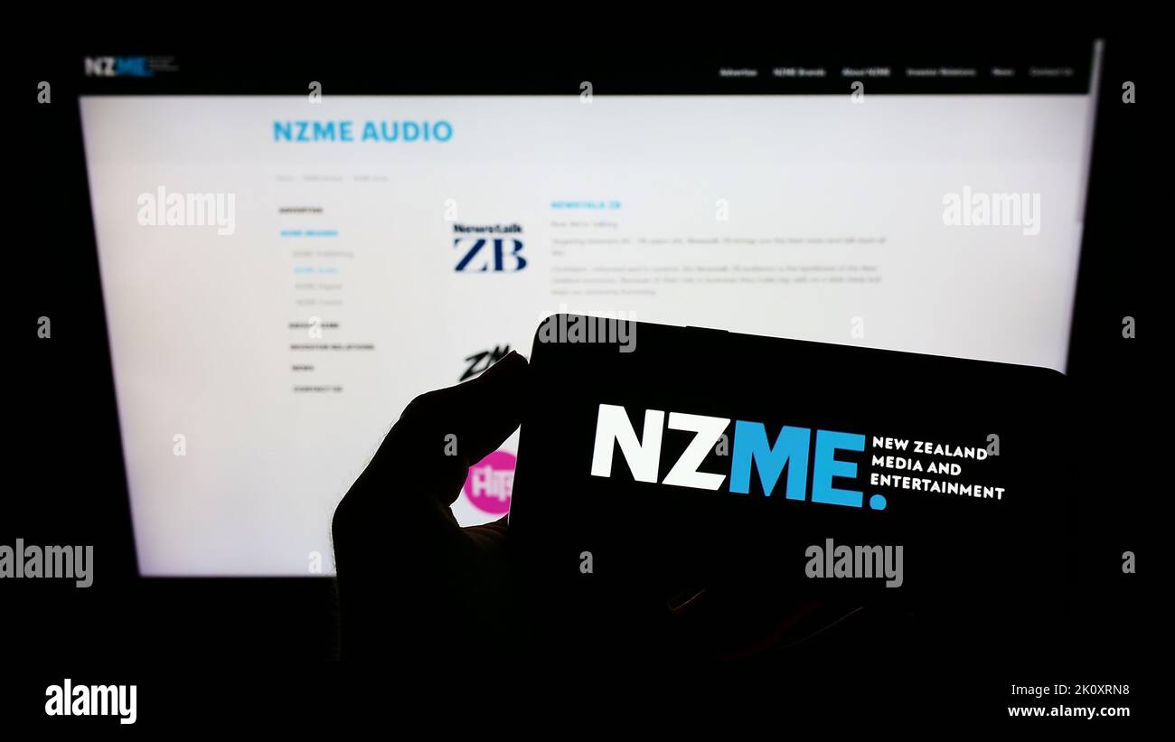 Person holding mobile phone with logo of company New Zealand Media and ...