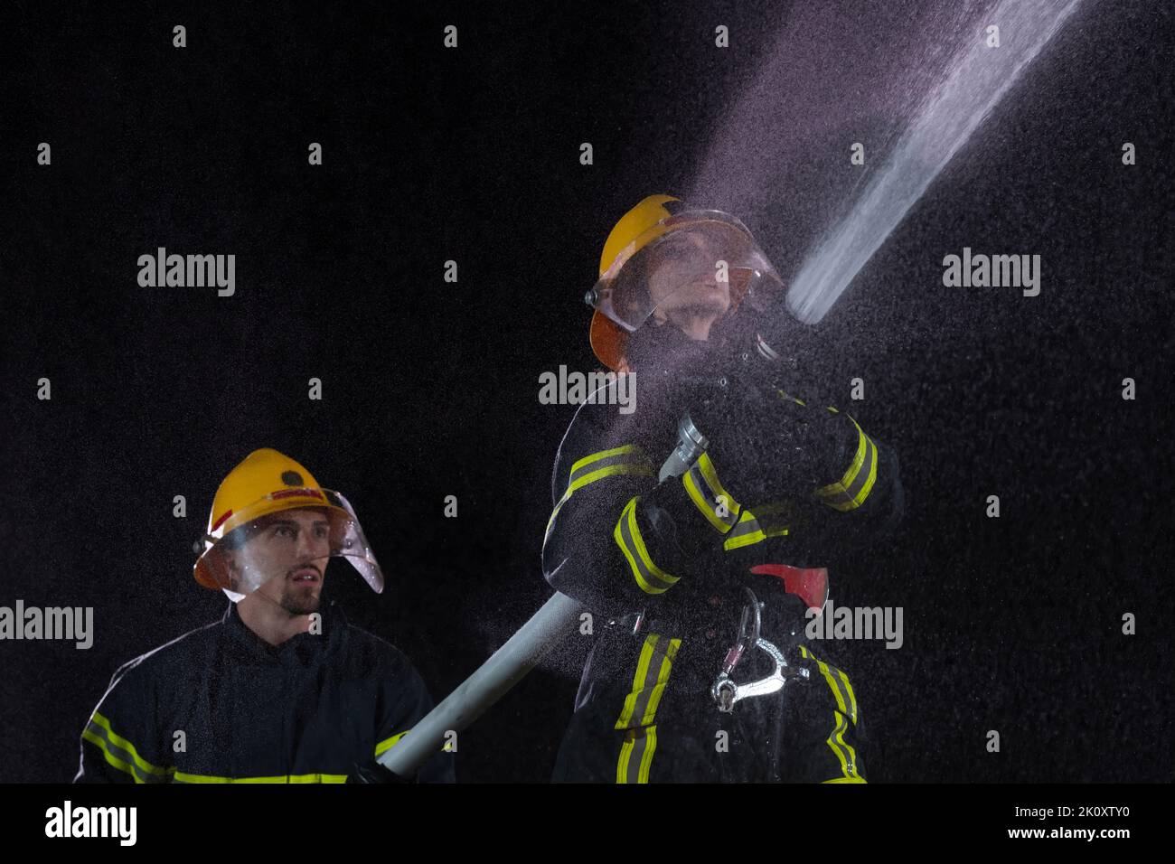Firefighters using a water hose to eliminate a fire hazard. Team of ...