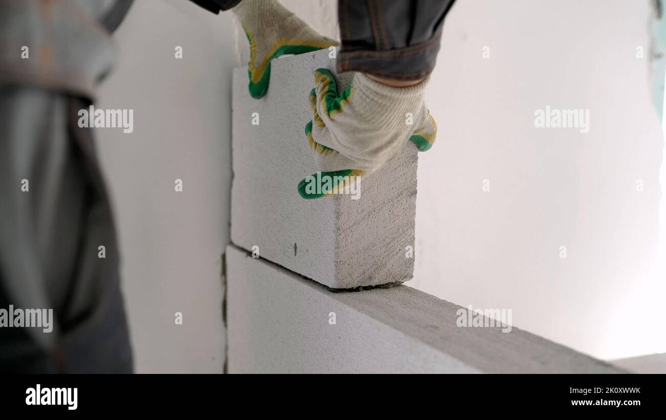 Builder laying a wall of gas blocks with tools and adhesive mortar ...