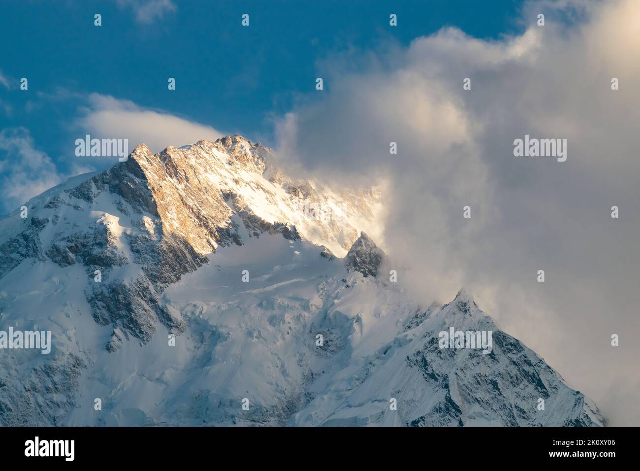 a beautiful shot of nanga parbat mountain peak and clouds covering a ...