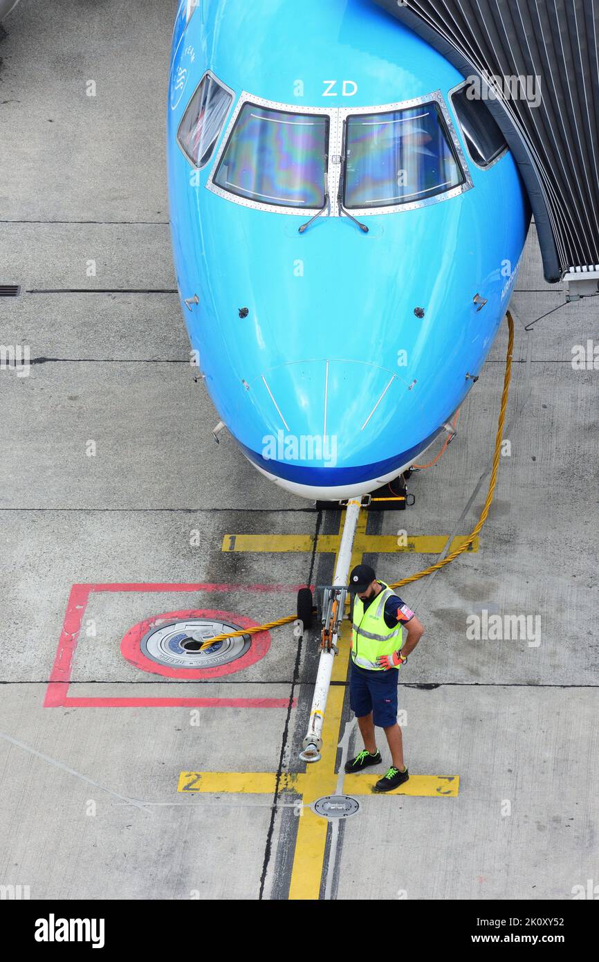 Aircraft with a blue nose cone on the runway with ground staff in ...