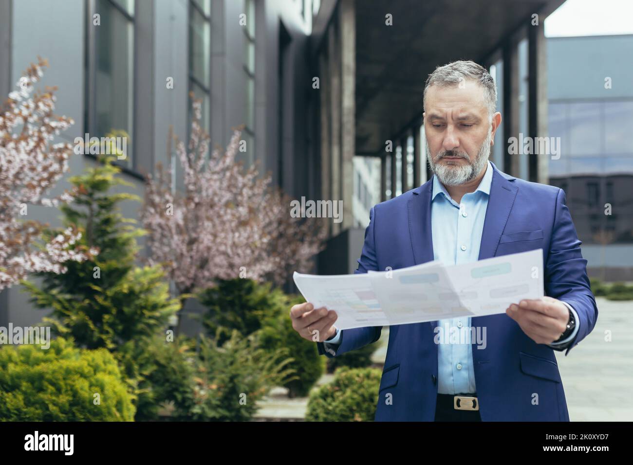 Real estate agent. Handsome senior serious man in suit and beard ...