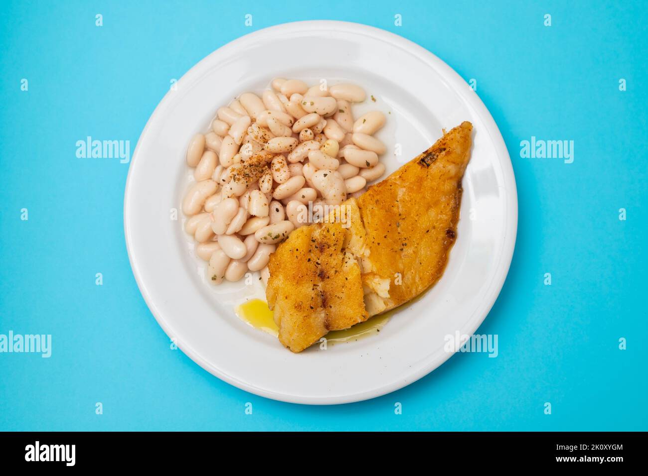 fried cod fish with white beans on the plate on blue paper Stock Photo ...