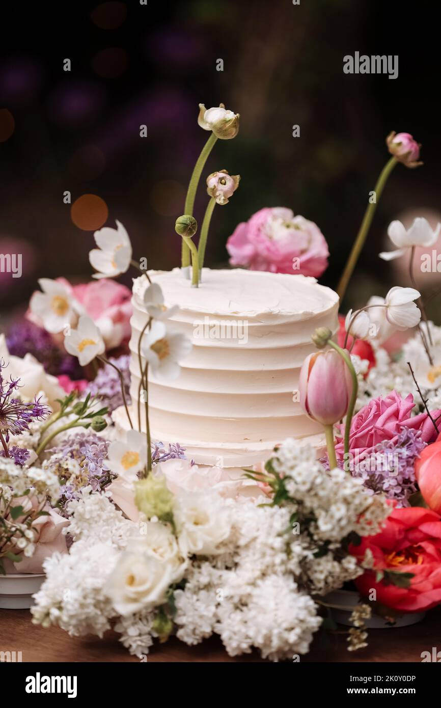 white wedding cake with fresh roses and wild flowers outdoors. Wedding ...