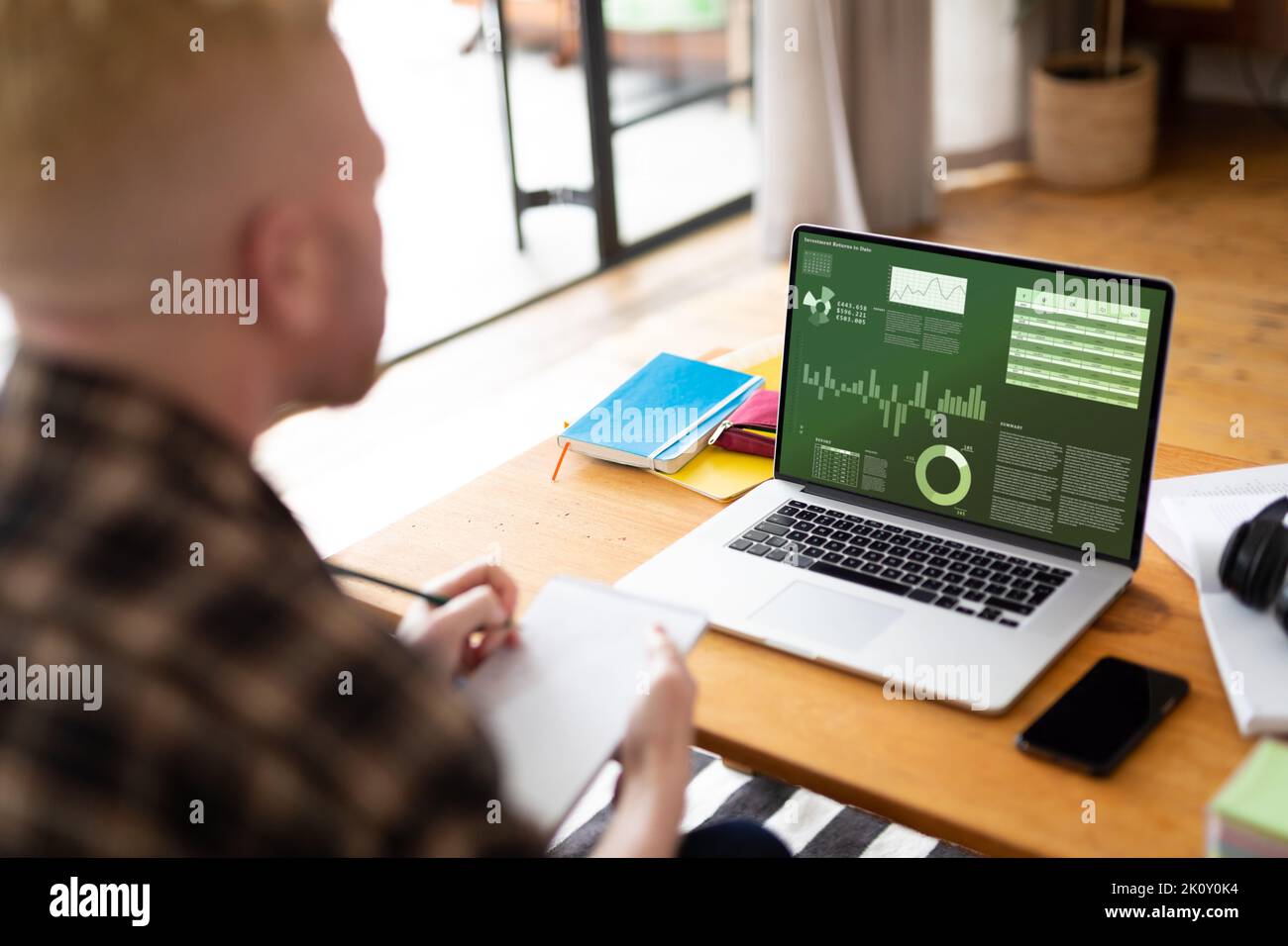 Albino african american man taking notes and using laptop, data ...
