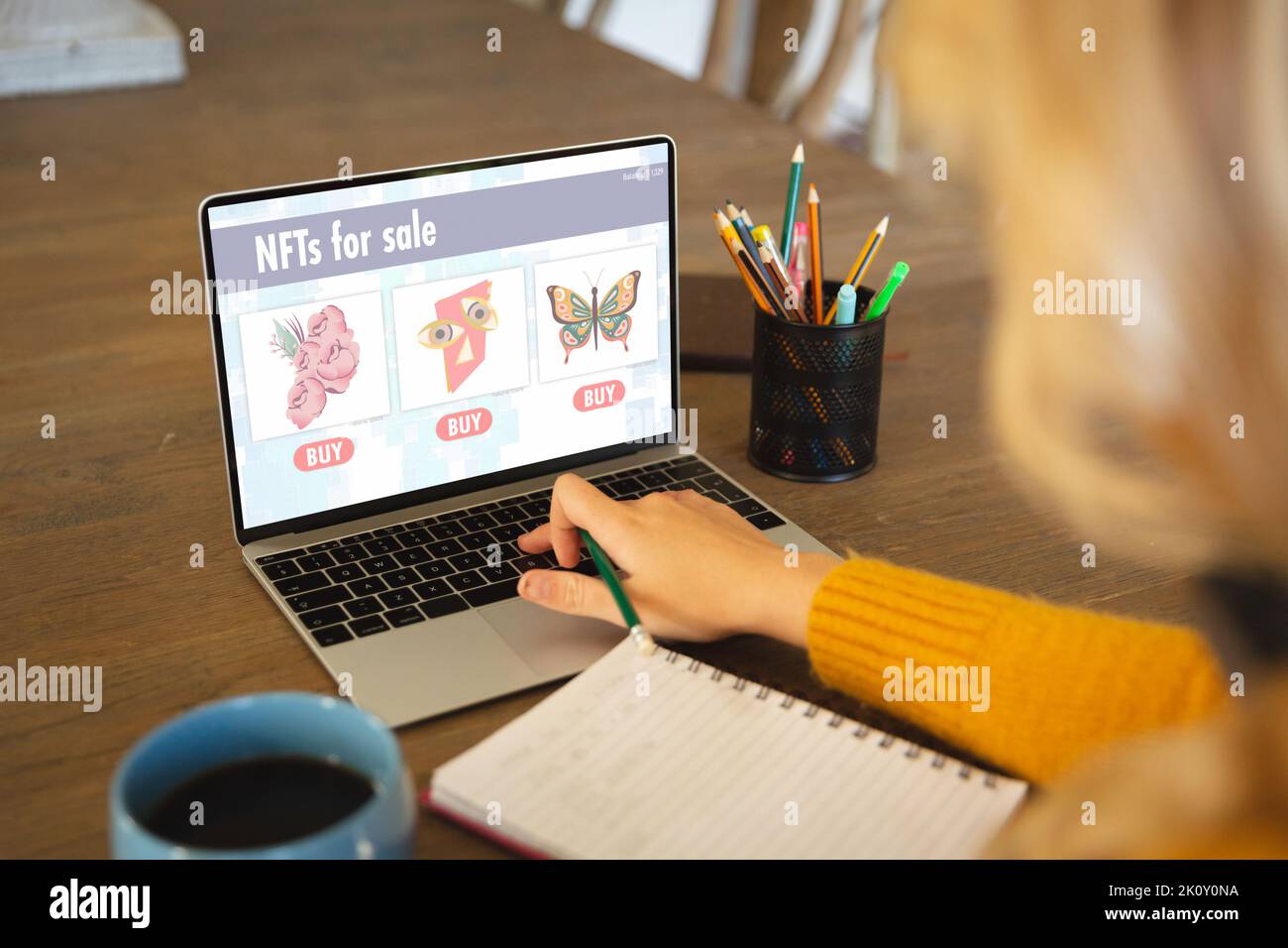 Caucasian businesswoman at table using laptop with nfts for sale on ...