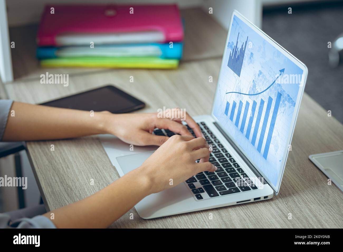 Hands of caucasian businesswoman at desk using laptop with graphs and ...