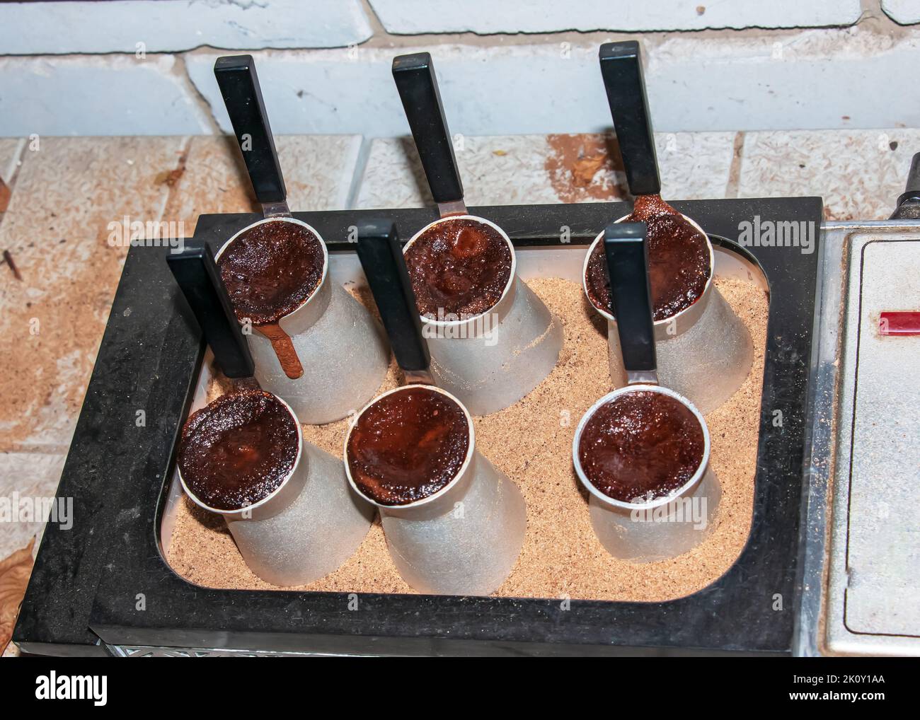 Traditional Turkish coffee with foam in cezve prepared on hot sand in ...